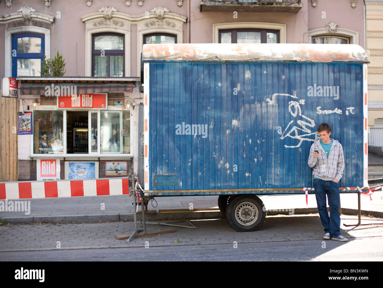 Young man standing in front of an old trailer Stock Photo - Alamy