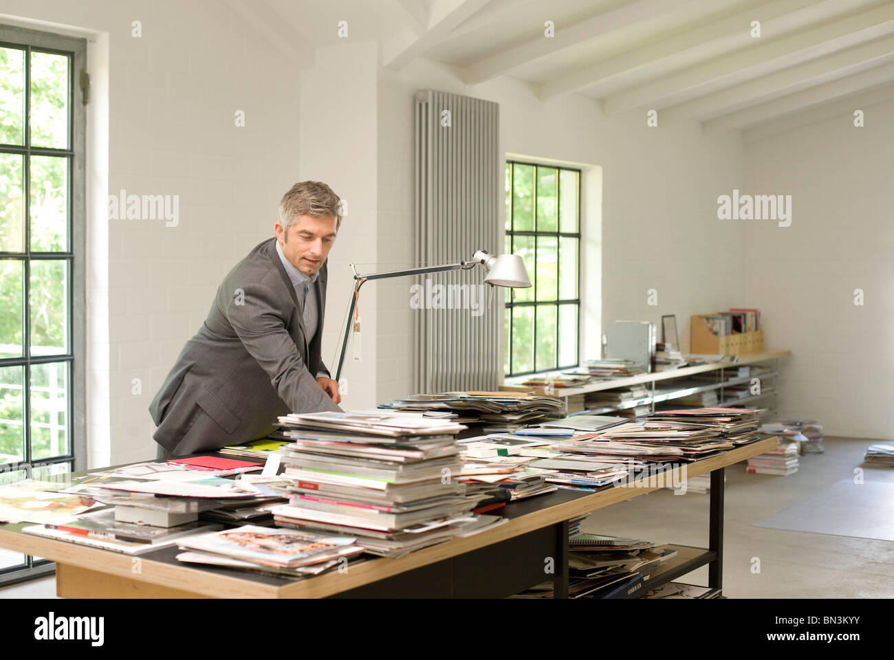 Man looking at magazines and books on a table Stock Photo - Alamy