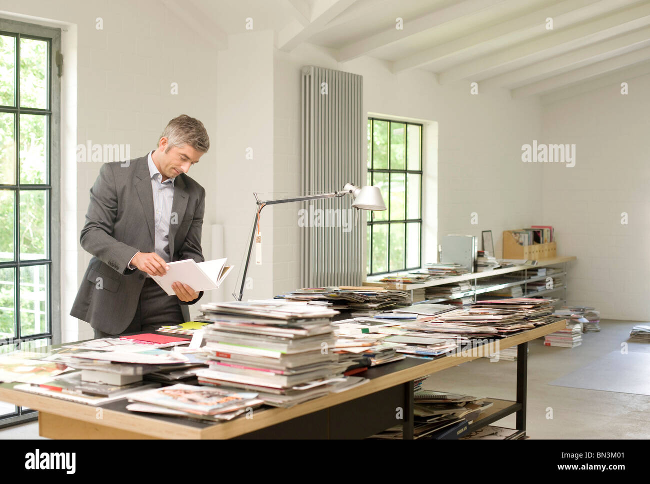 Man standing in front of a table with magazines and books and reading a ...
