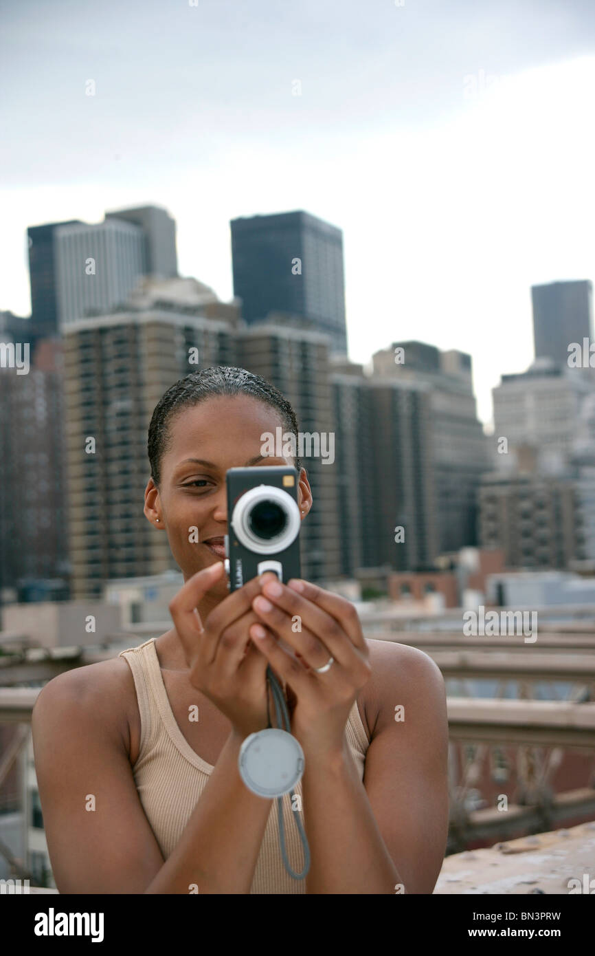 Woman taking picture with a camera, skyline of New York in the ...