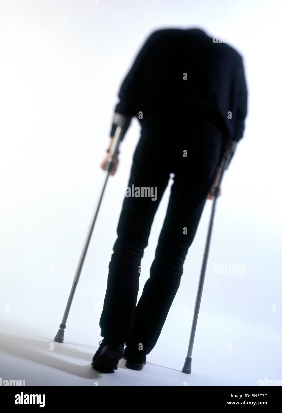 Rear view of man walking with crutches Stock Photo - Alamy