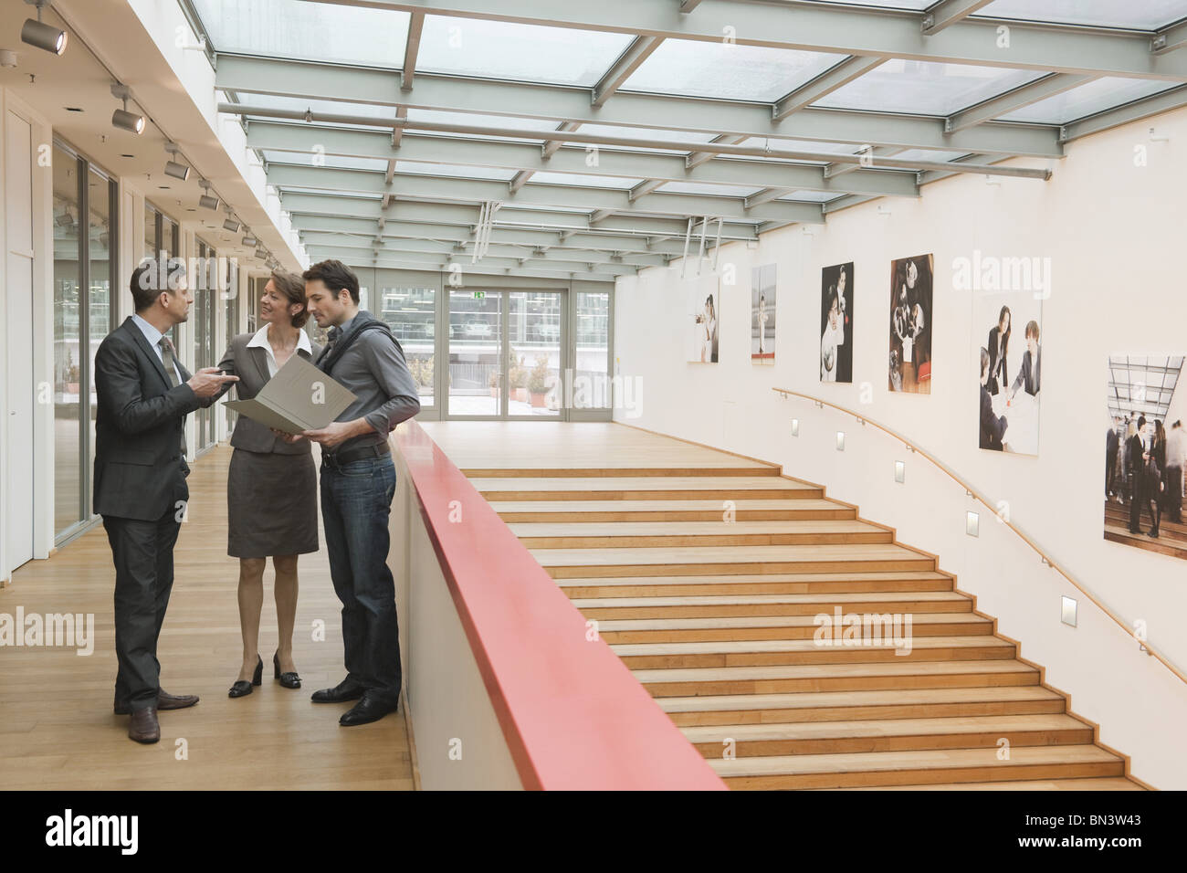 Three people standing in office building Stock Photo - Alamy