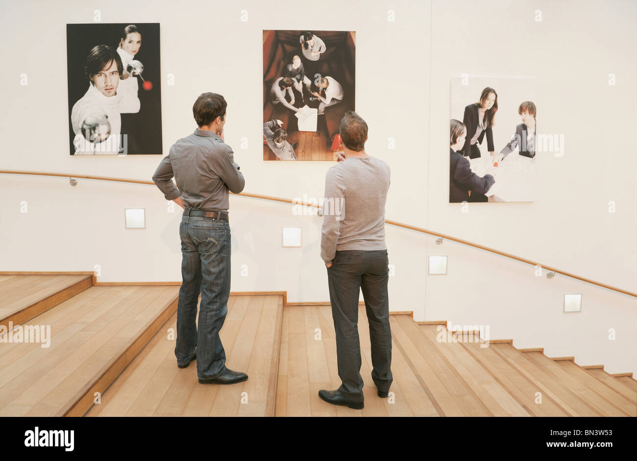 two men looking at photos on wall Stock Photo - Alamy