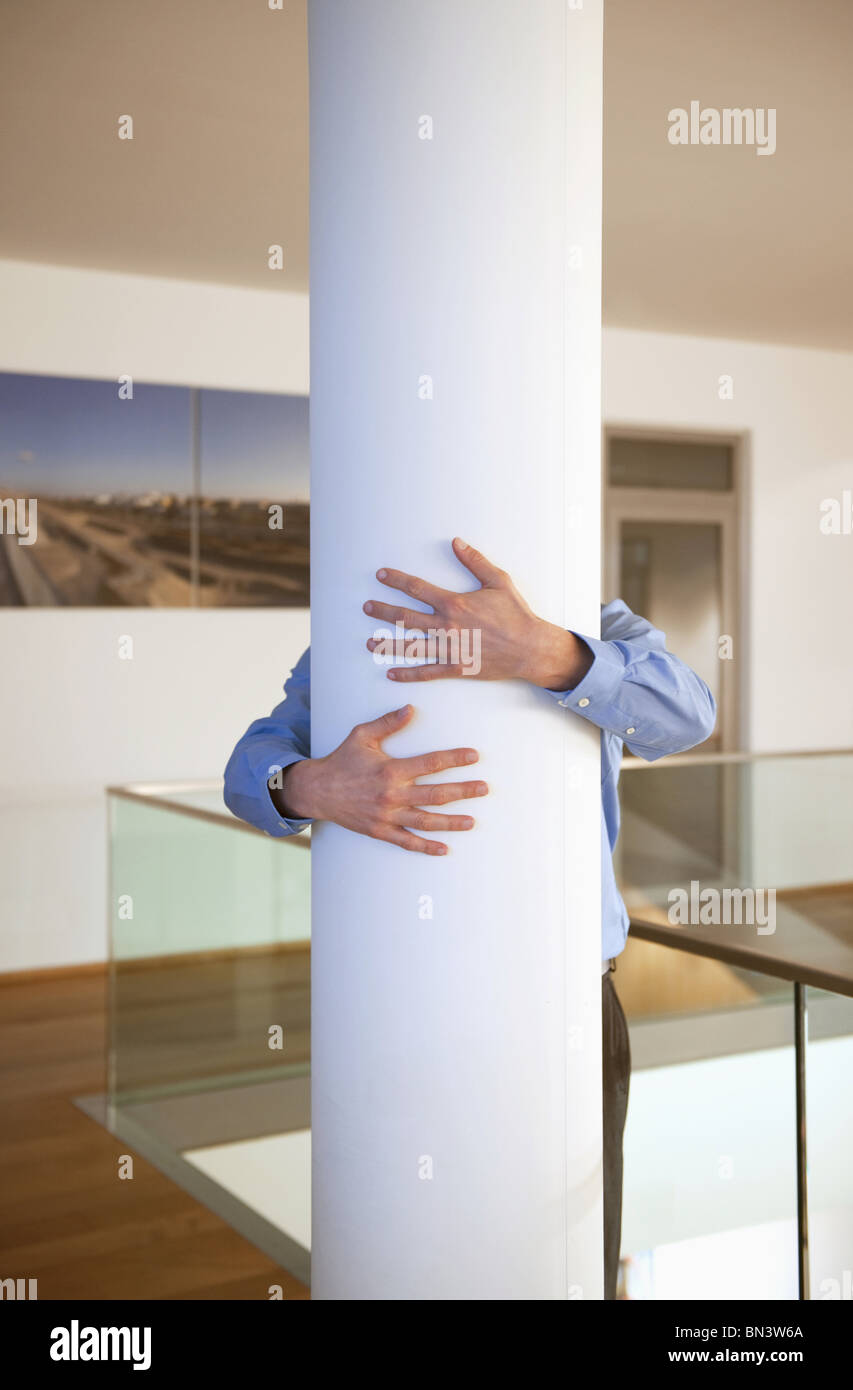 Man standing behind column Stock Photo - Alamy