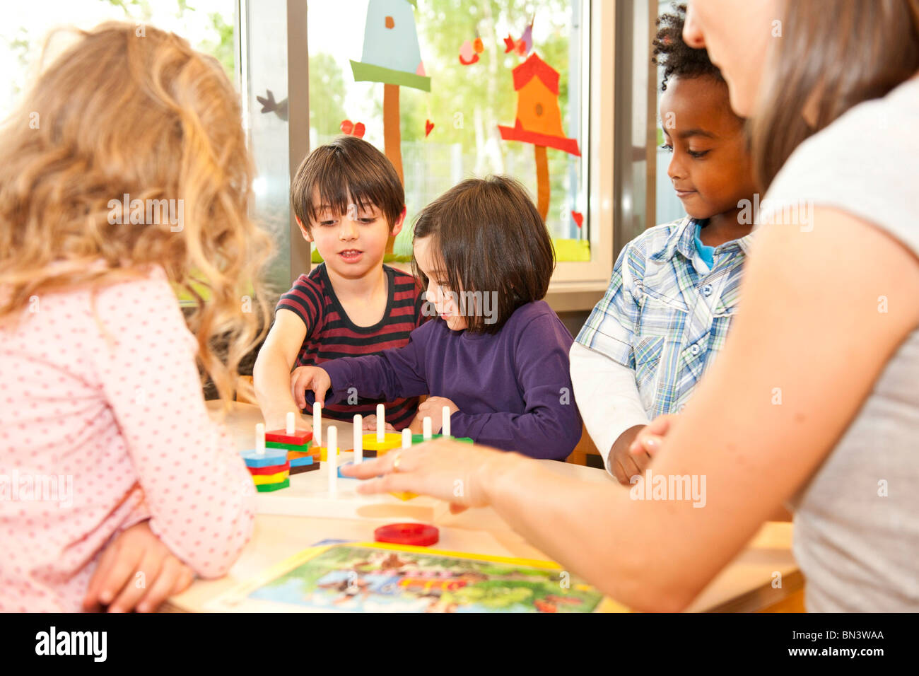 Kindergarten teacher playing children Stock Photo - Alamy