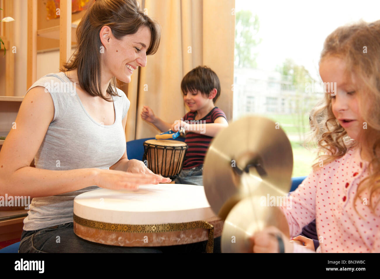Kindergarten teacher and children making music Stock Photo - Alamy