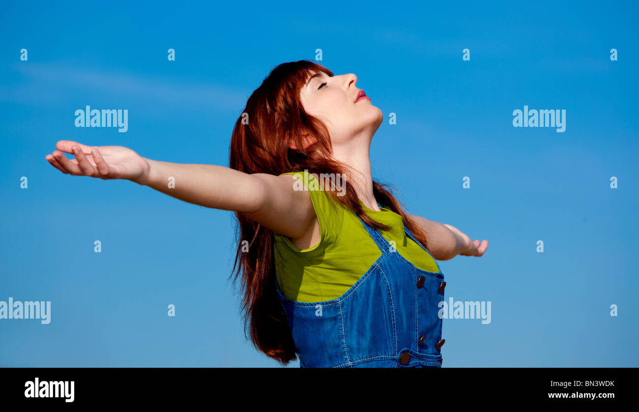 Portrait of a beautiful woman over a blue sky with arms open Stock ...