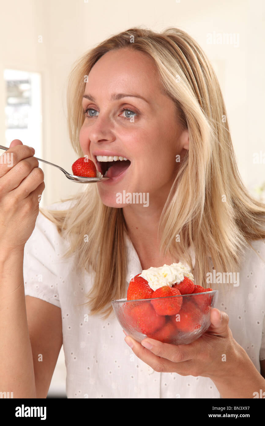 WOMAN EATING STRAWBERRIES AND CREAM Stock Photo - Alamy