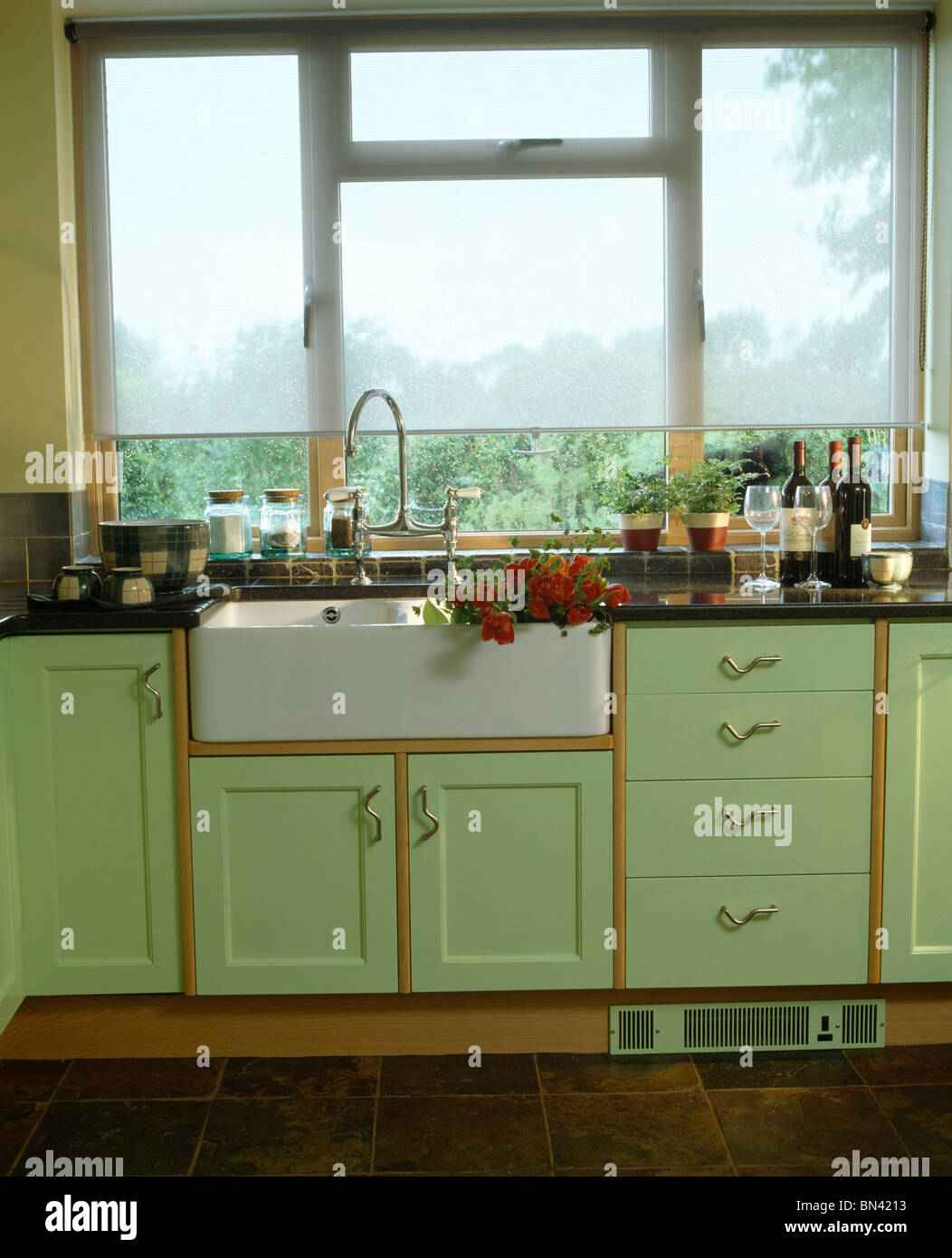 White blind on window above Belfast sink in country kitchen with pale ...