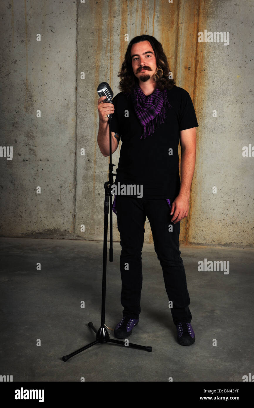Man standing by vintage microphone in industrial grunge background ...