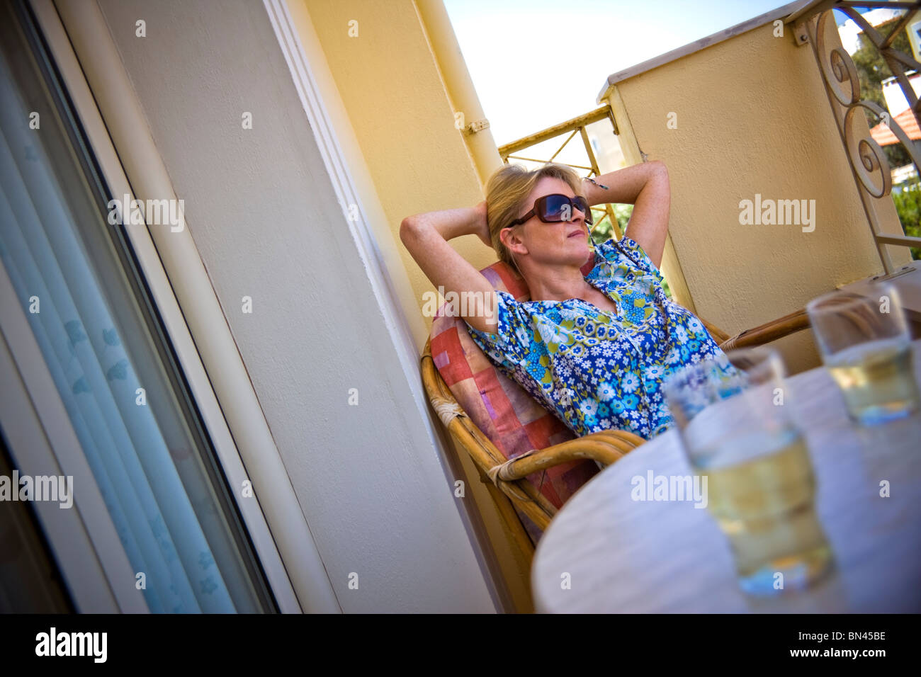 WOMAN RELAXING ON A BALCONY IN GREECE Stock Photo - Alamy