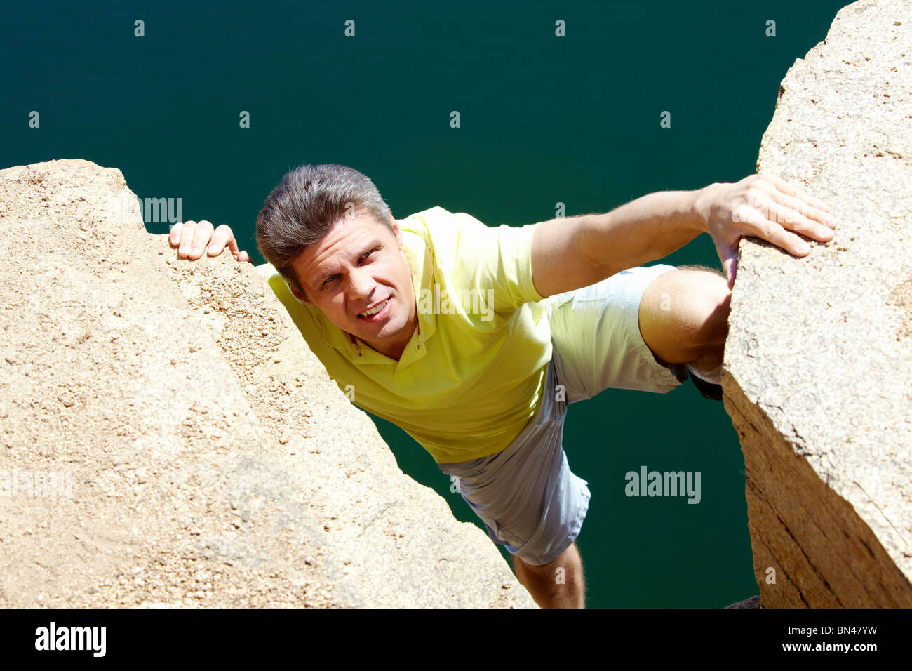 Image of man climbing over rock on background of water outdoors Stock ...