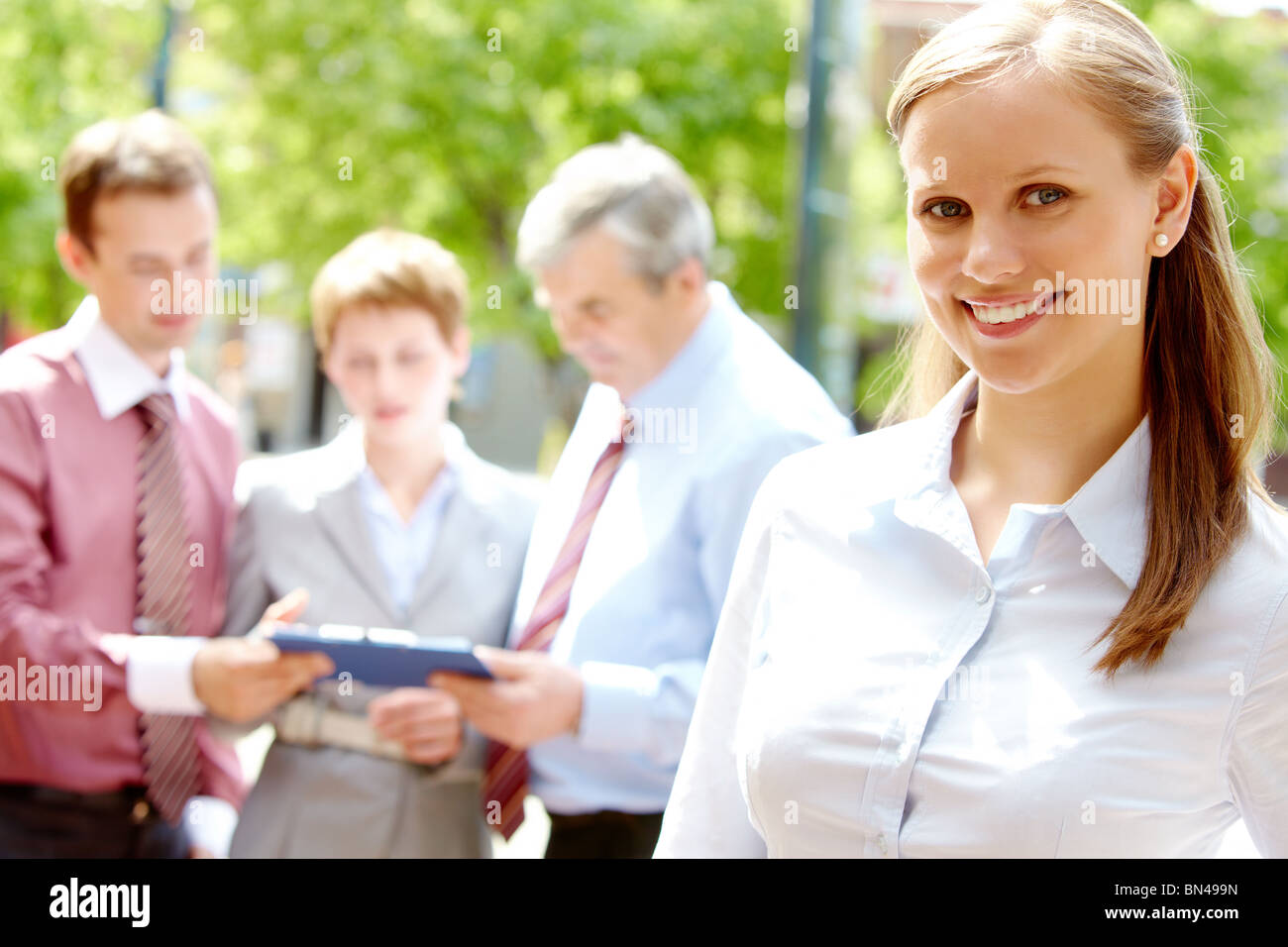 Portrait of pretty employee smiling at camera in a natural environment ...