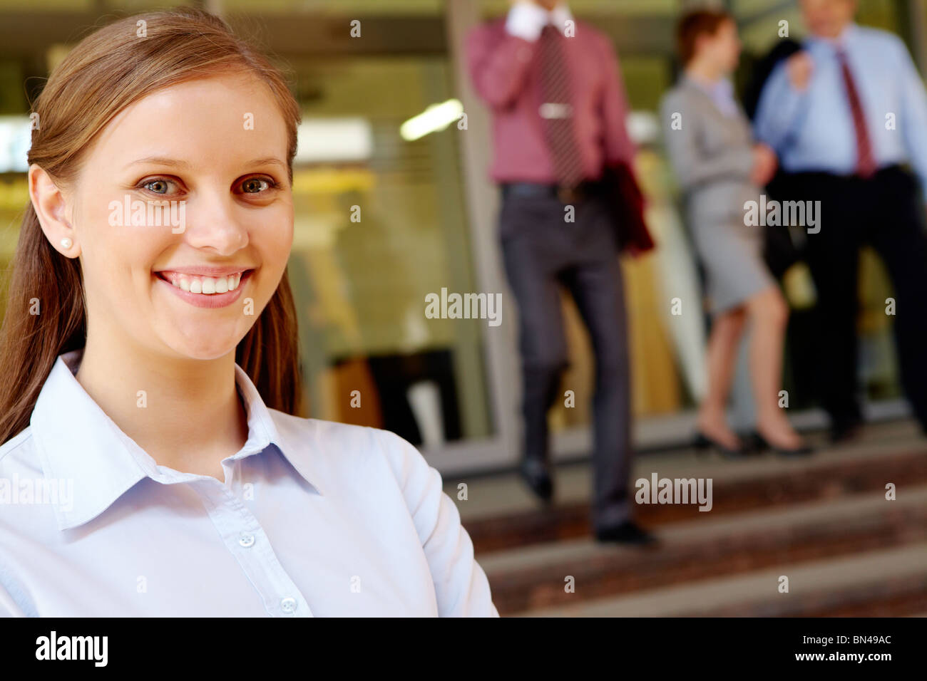 Portrait of pretty employee smiling at camera with her partners on ...