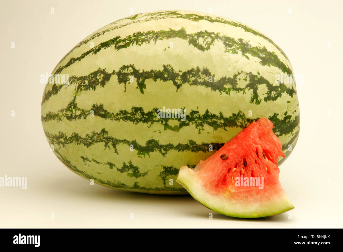 One full watermelon and one cut slice showing pulp and black seeds with ...