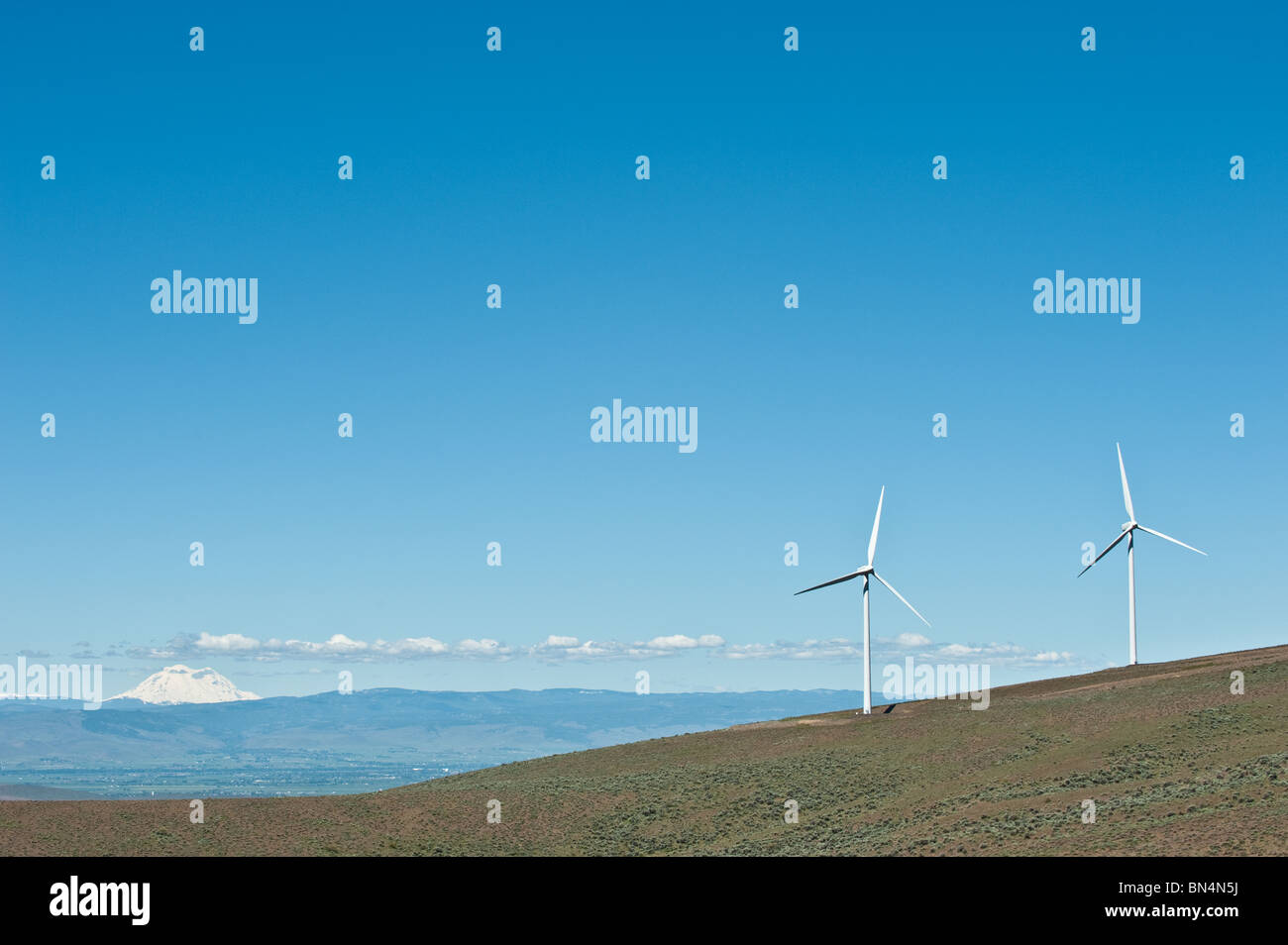 Giant clean energy wind turbines on a mountain ridge with a snow capped ...