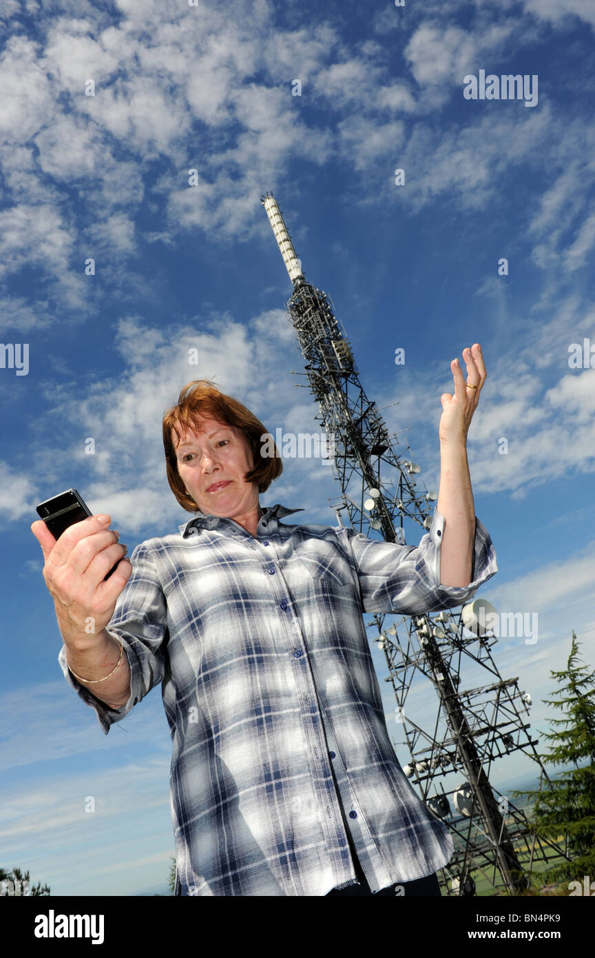 Woman using a mobile phone next to the The Wrekin transmitting station ...