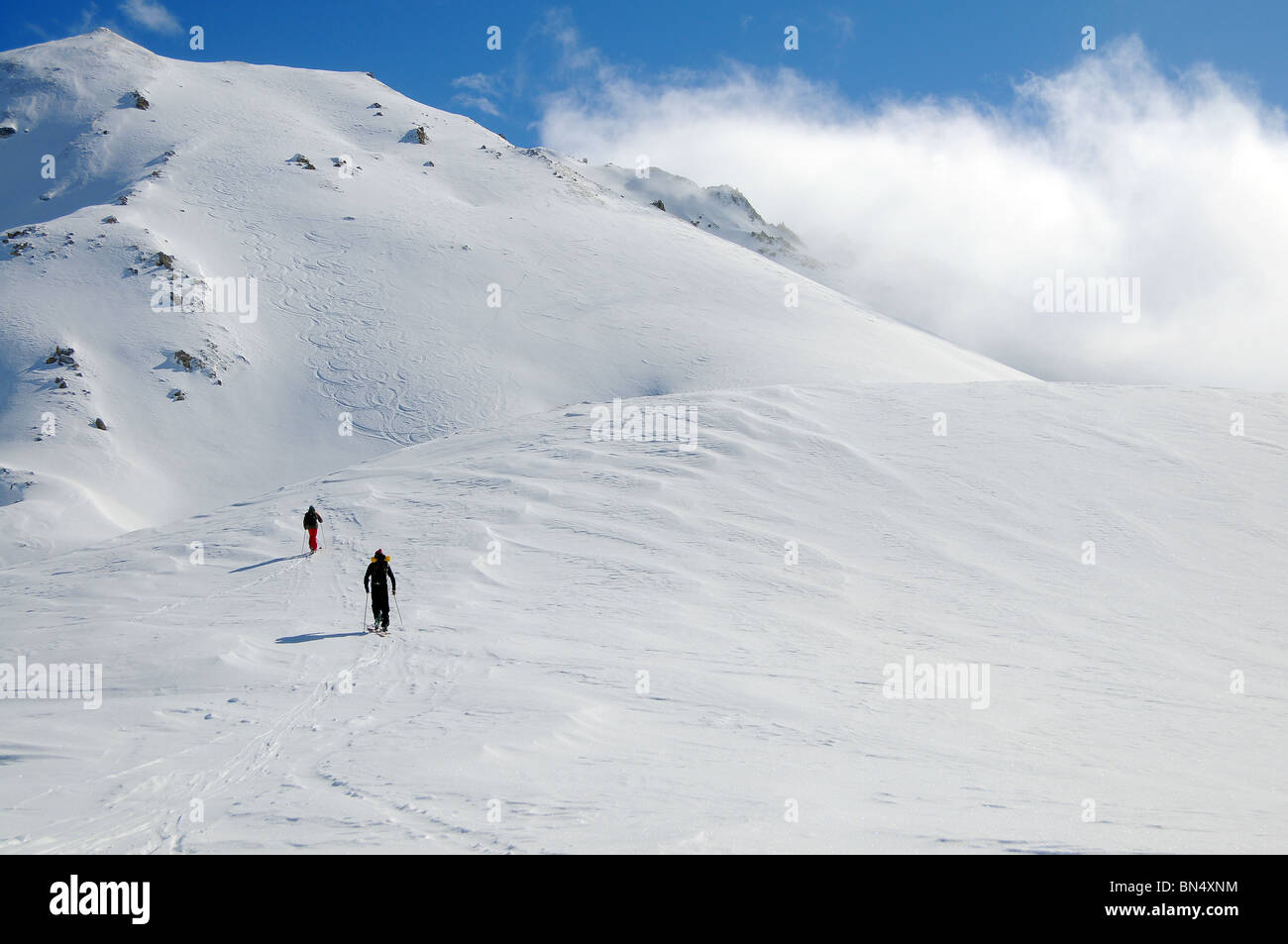 A group of skiers tour through the mountains off-piste between the ...