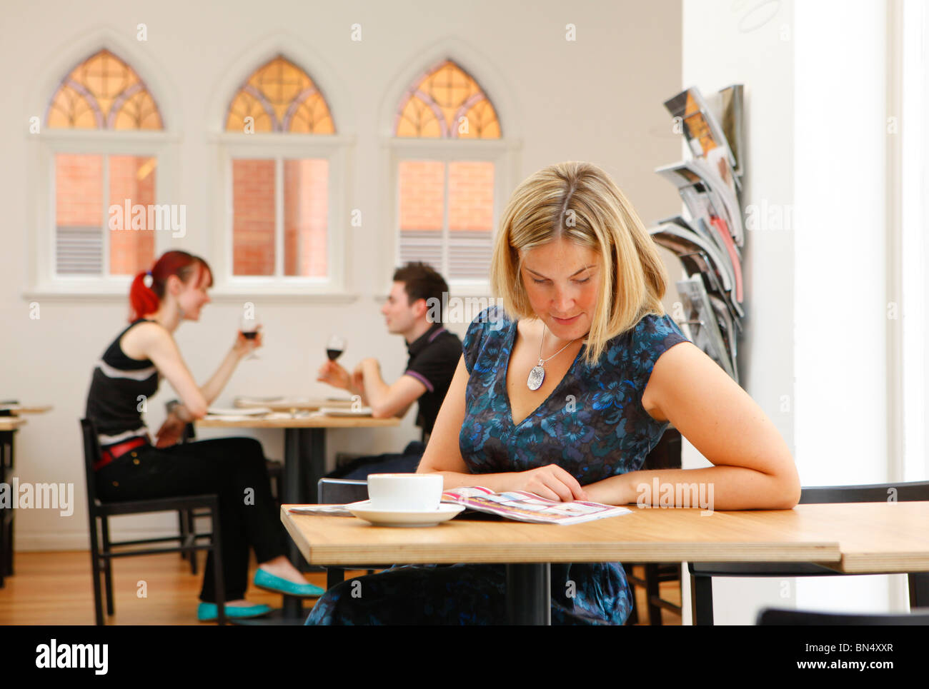 Woman sat reading at a table Stock Photo - Alamy