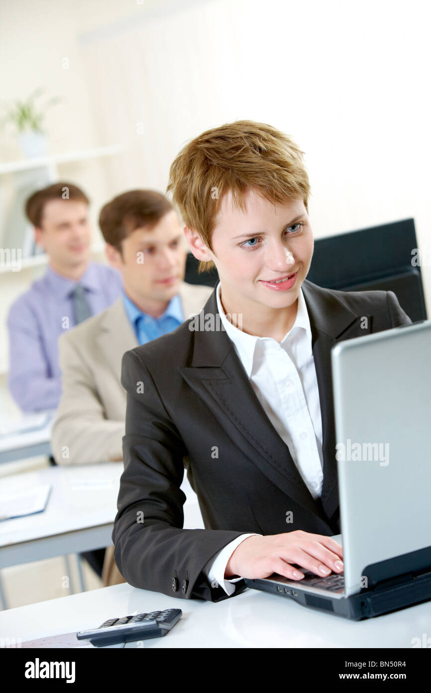 Pretty employee typing on background of working colleagues in the ...