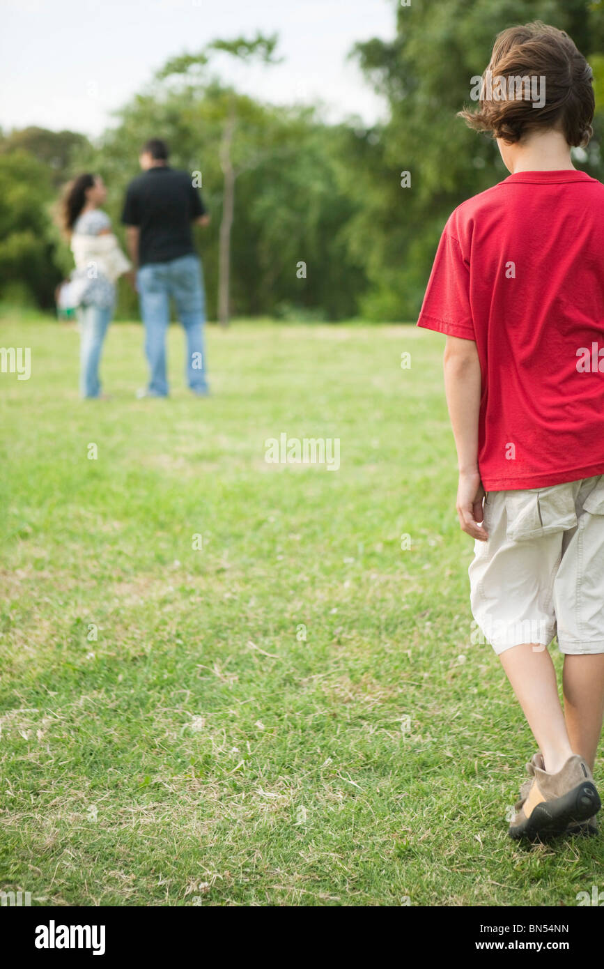 Boy walking sulkily toward parents having conversation distance Stock ...