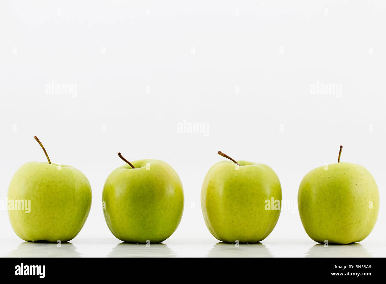 four green apples on white background Stock Photo - Alamy