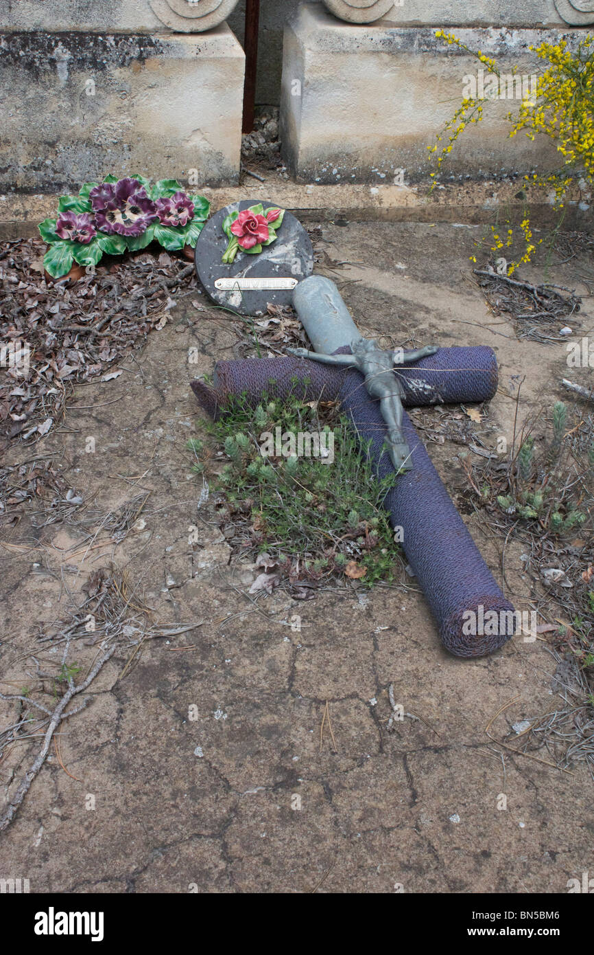 faded cross, wrapped in blue bead-work, on old tomb in a French ...
