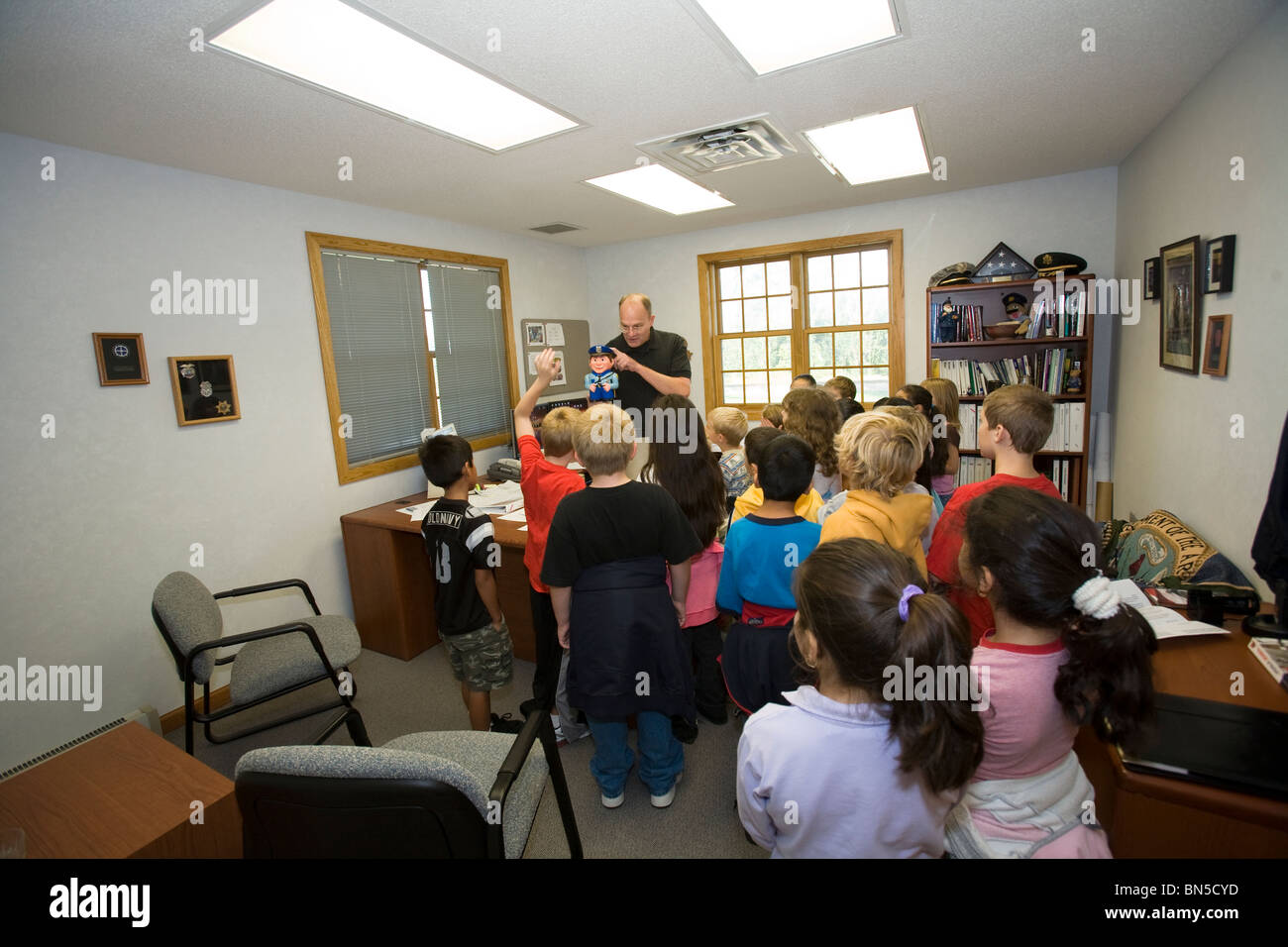 School children visiting small town police department. Young kids with ...