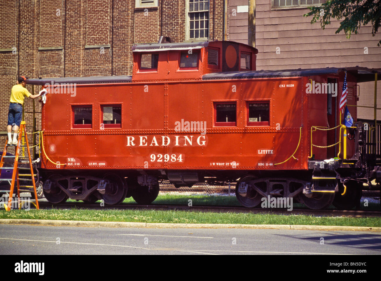 Volunteer helps clean maintain red caboose Reading RR company Stock ...