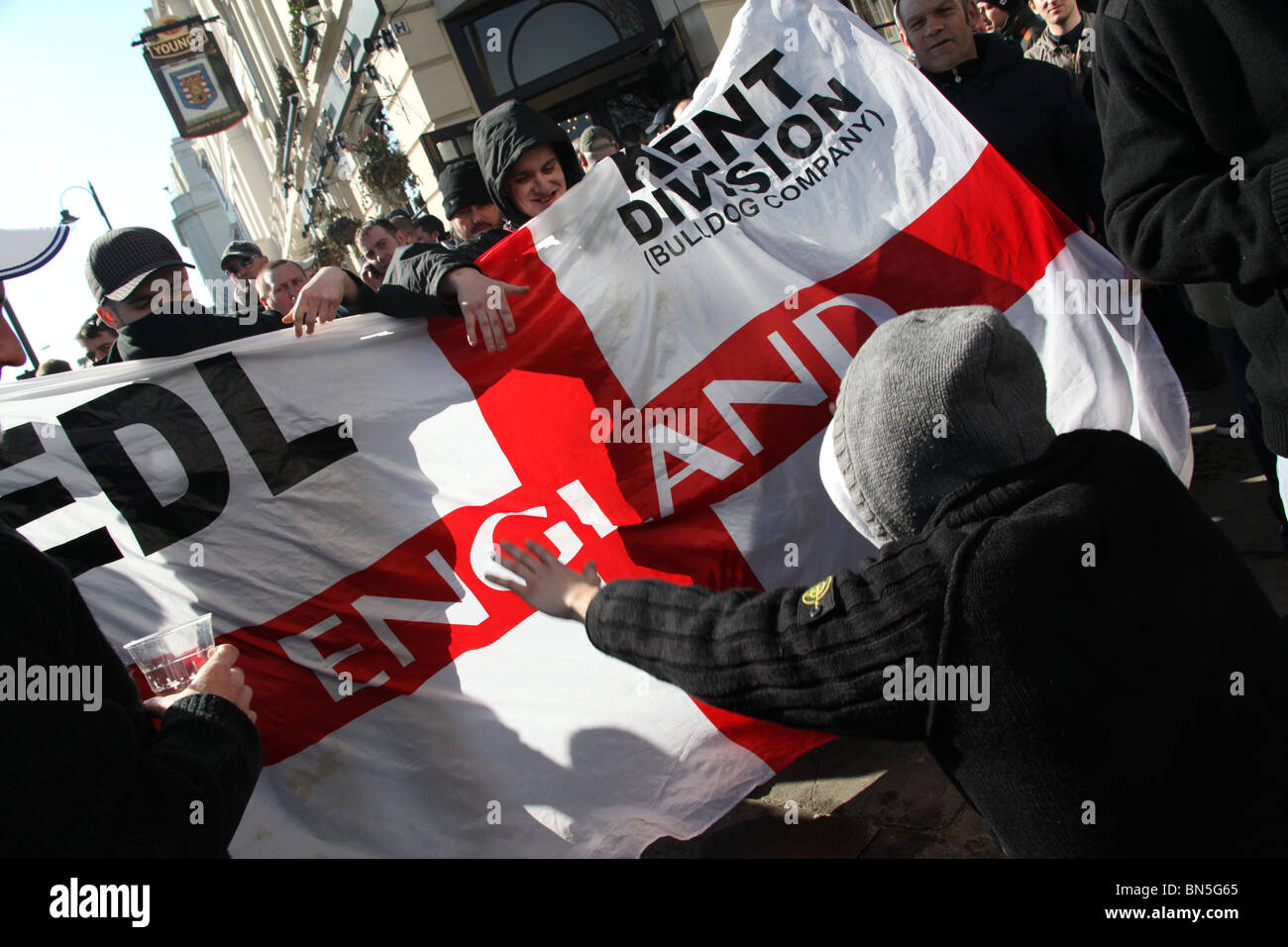An English Defence League protester bows to an EDL flag during a rally ...