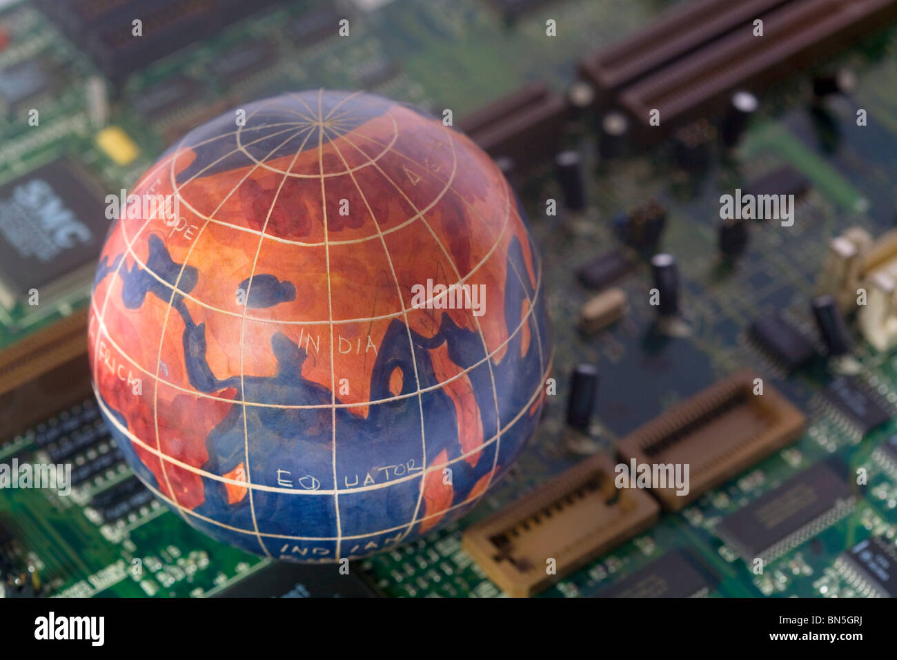 A globe with Asia in view on a motherboard representing global ...