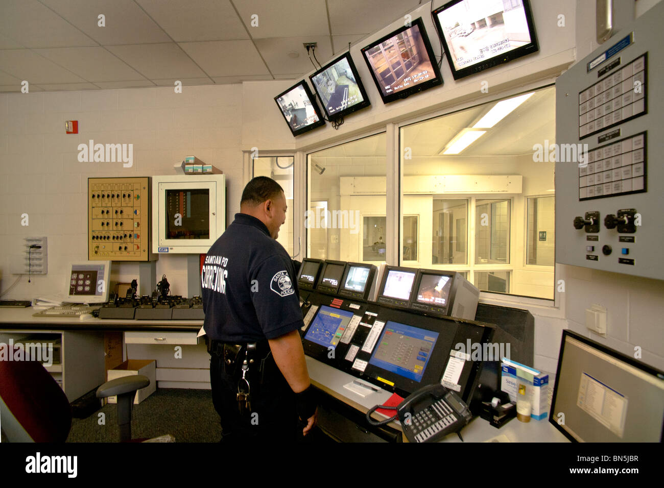 Uniformed Hispanic corrections officer operates the electronic security ...