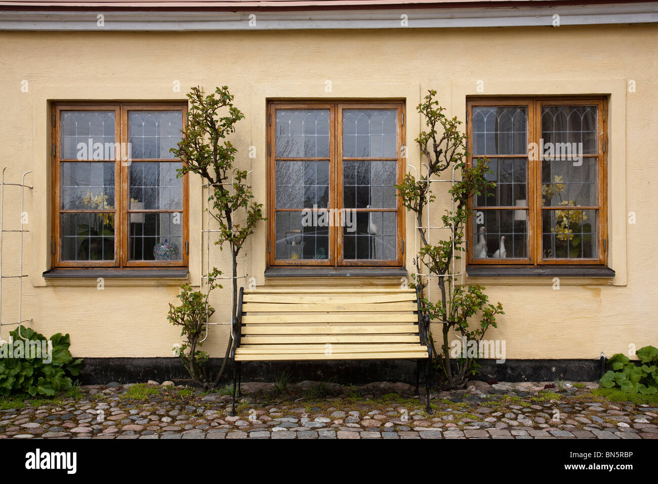 Yellow house-facade with wooden bench Stock Photo - Alamy