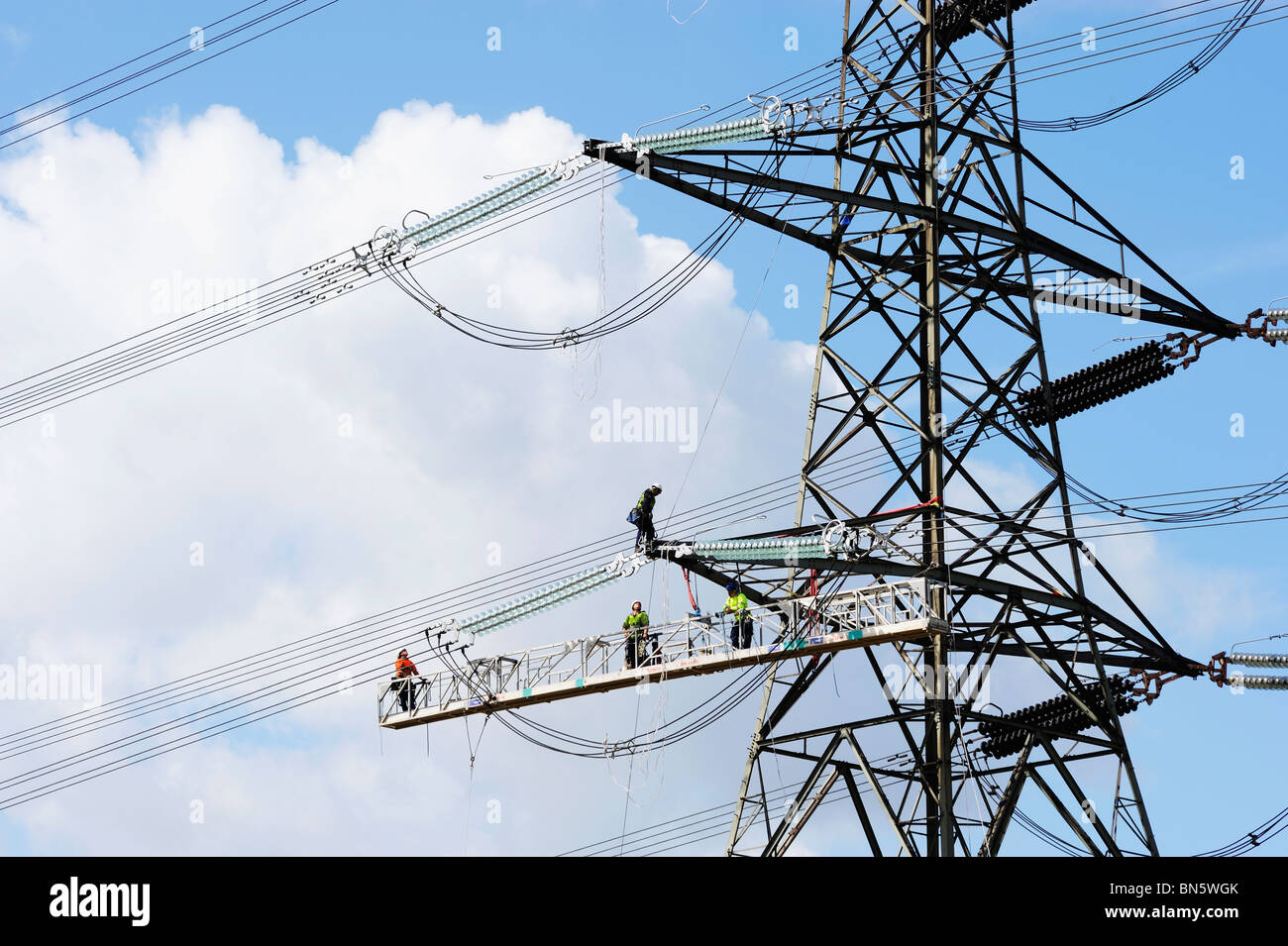Electrical engineers maintaining high voltage lines on pylons Stock ...