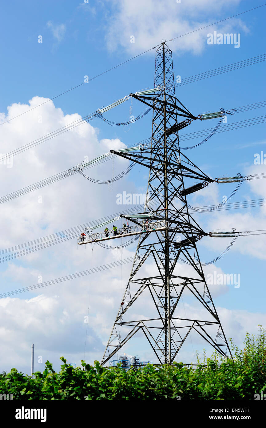 Electrical engineers maintaining high voltage lines on pylons Stock ...