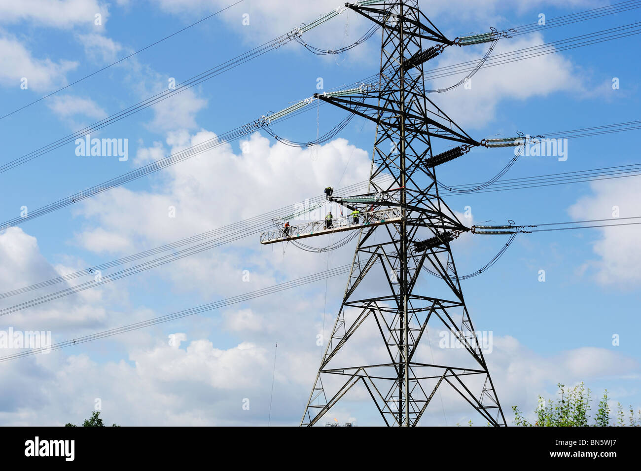 Electrical engineers maintaining high voltage lines on pylons Stock ...