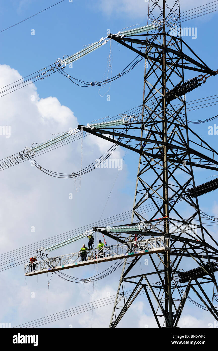Electrical engineers maintaining high voltage lines on pylons Stock ...