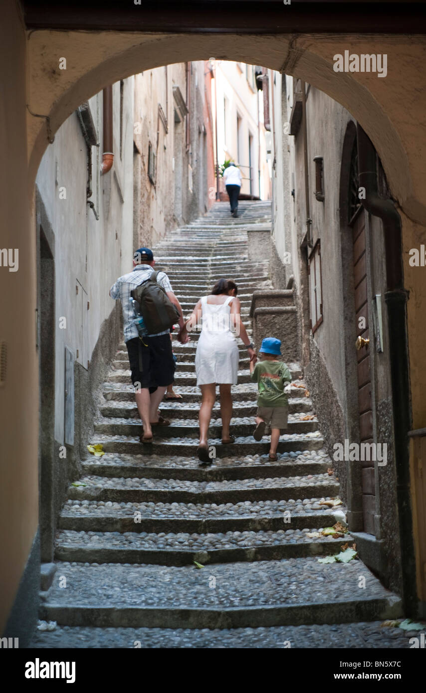 A young family climbing the cobbled stairs in a small alley in Bellagio ...