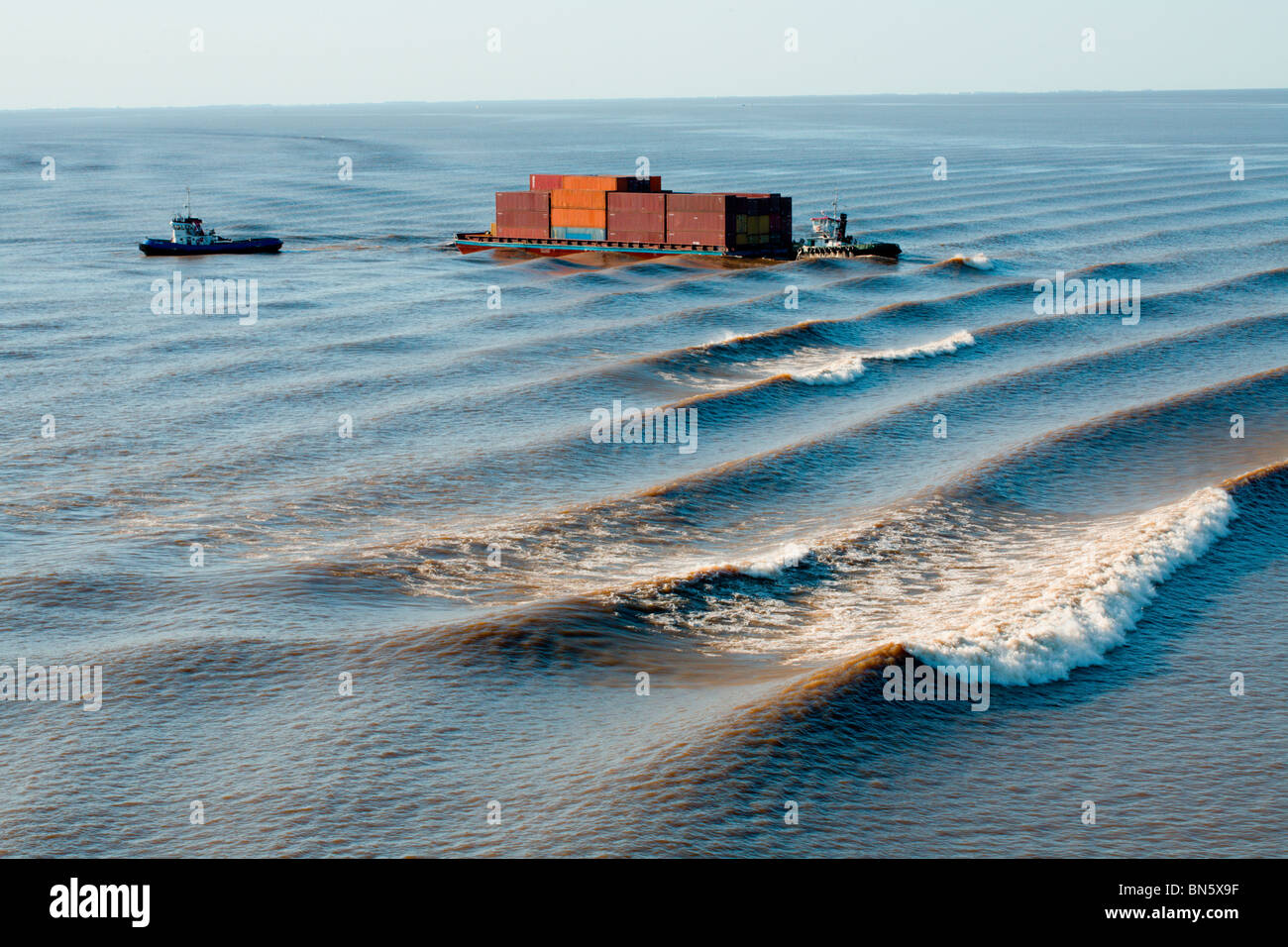 barge with cargo being towed by two tug boats over waves Stock Photo ...