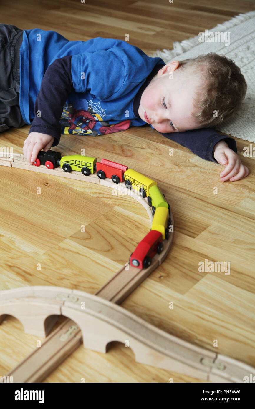 Toddler boy playing with a traditional wooden train set at home MODEL ...