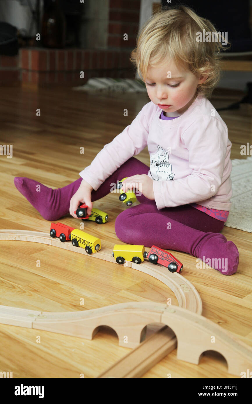 Toddler girl playing with a traditional wooden train set at home MODEL ...
