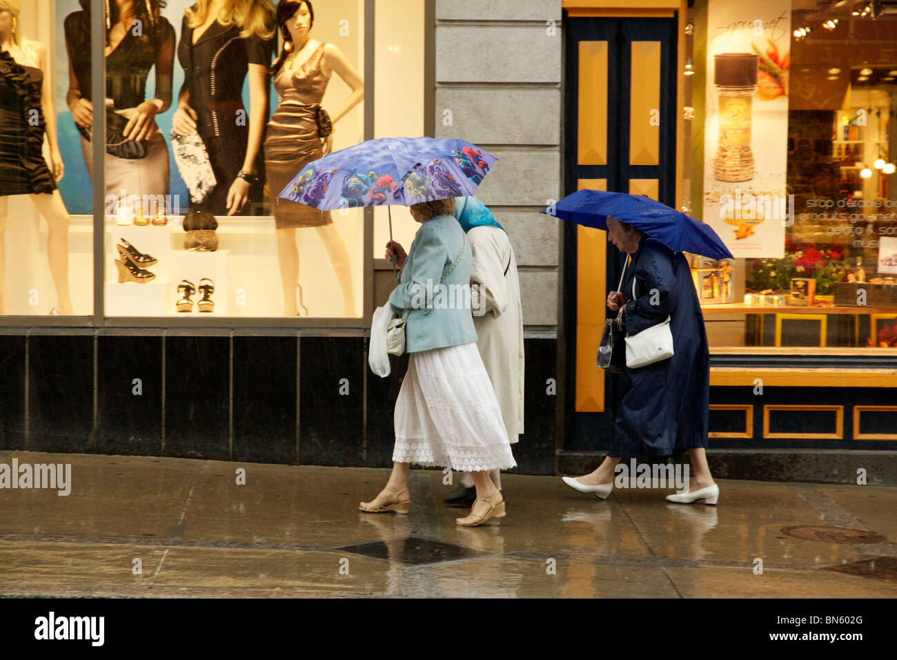 Three women with umbrellas on a rainy day. Rue Saint-Jean, Quebec City ...