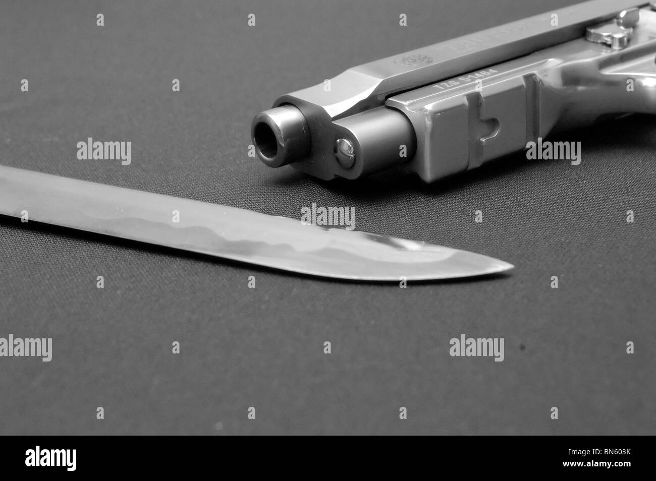 A blacka and white image of a diagonal view of a pistol against a blade ...
