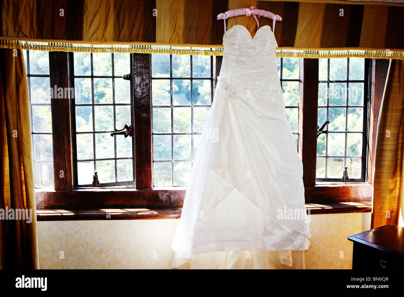 White wedding dress hanging up in front of window on wedding day Stock ...