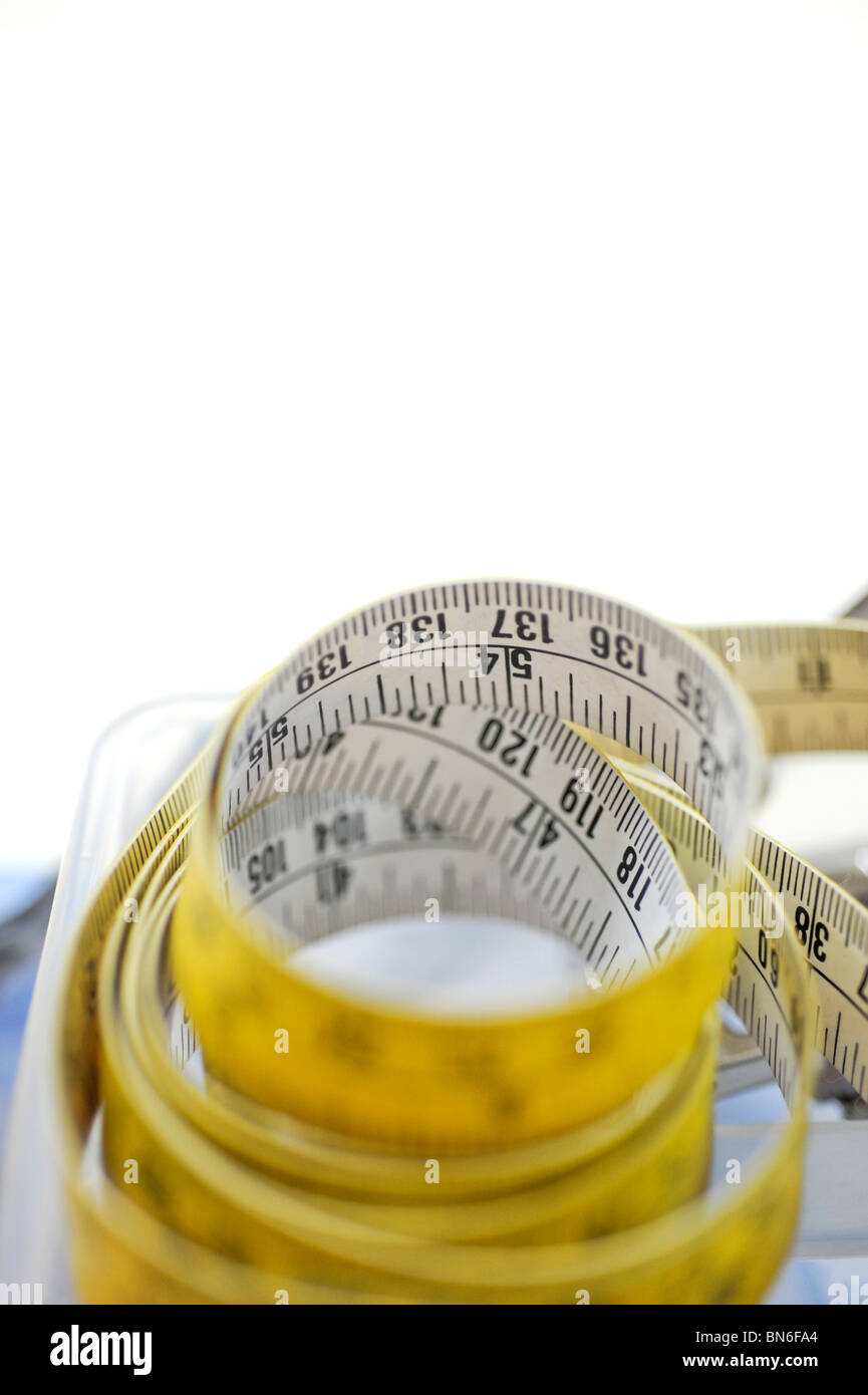 A curled up tape measure on needlework bench Stock Photo - Alamy