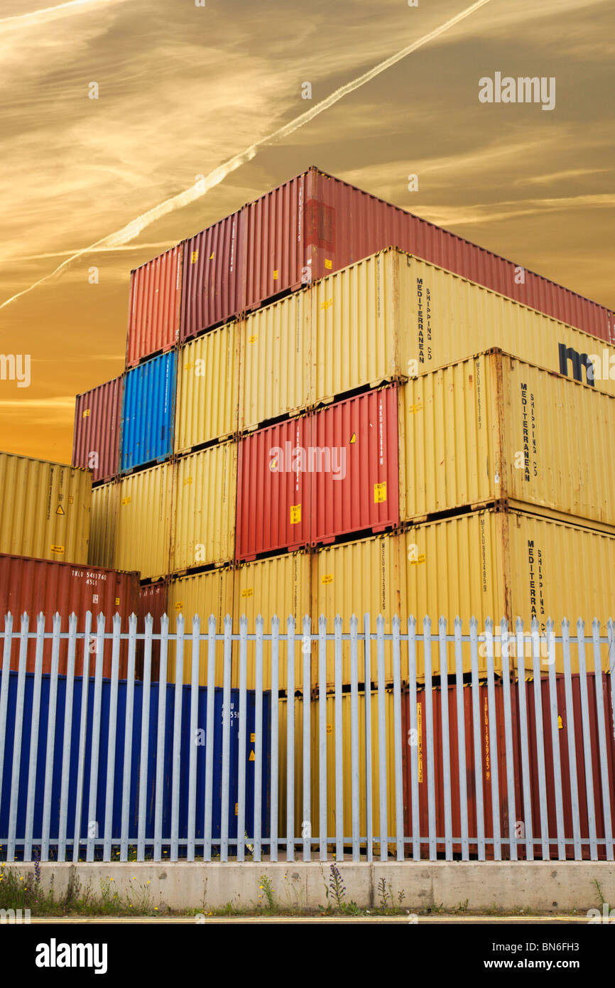 Shipping containers behind a security fence with jet trails overhead ...