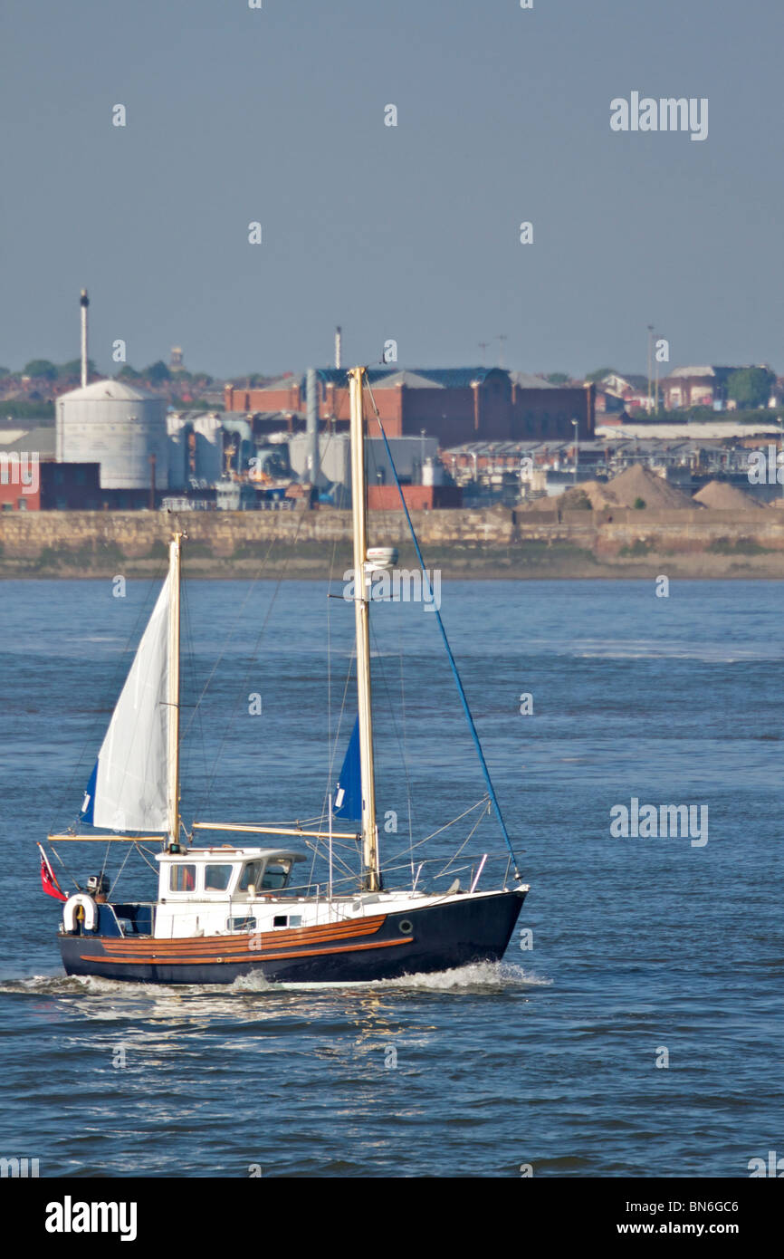 Small sailing boat heading up river Mersey on a bright sunny evening ...