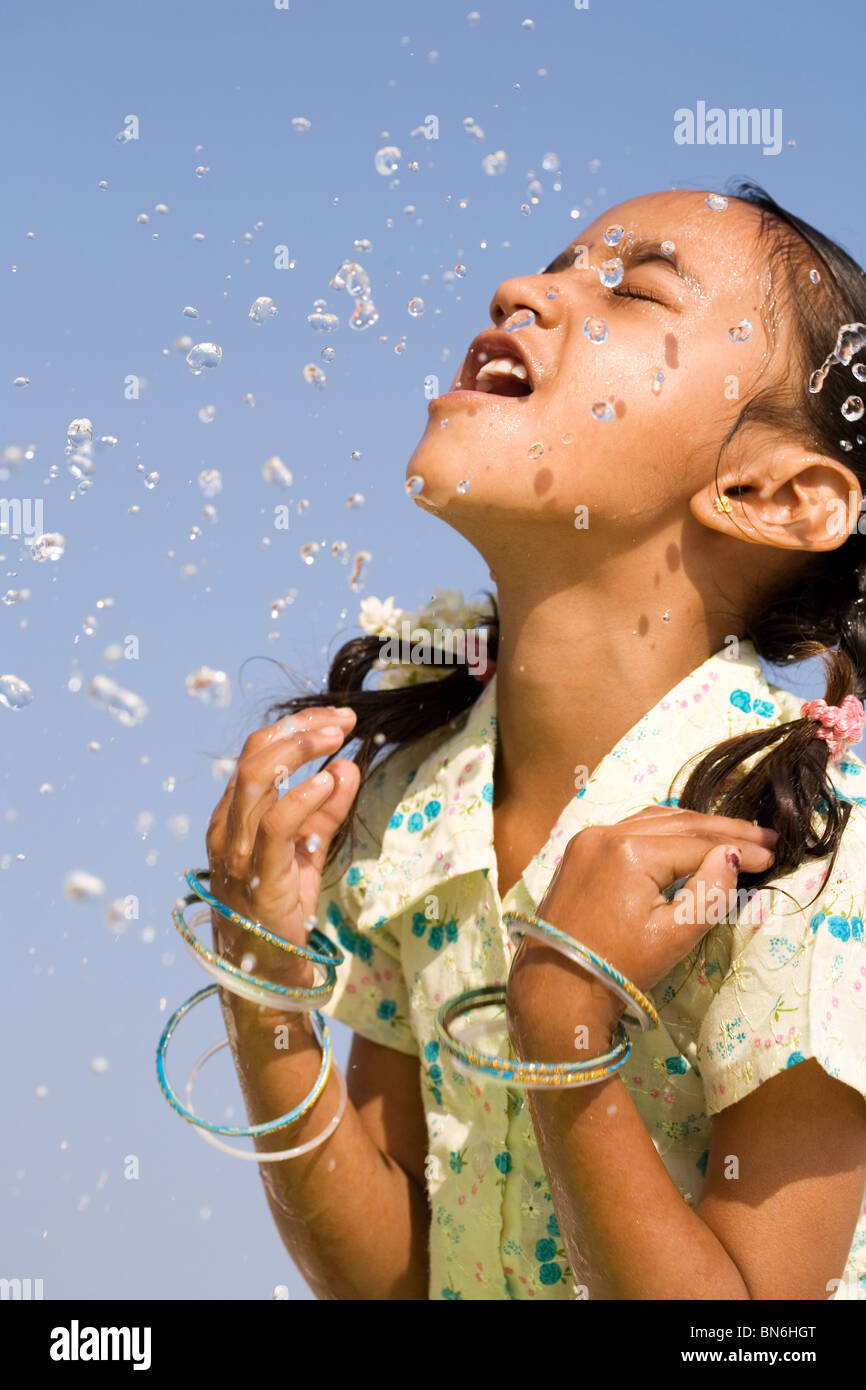 Indian girl splashing water on himself against a blue sky. India Stock ...