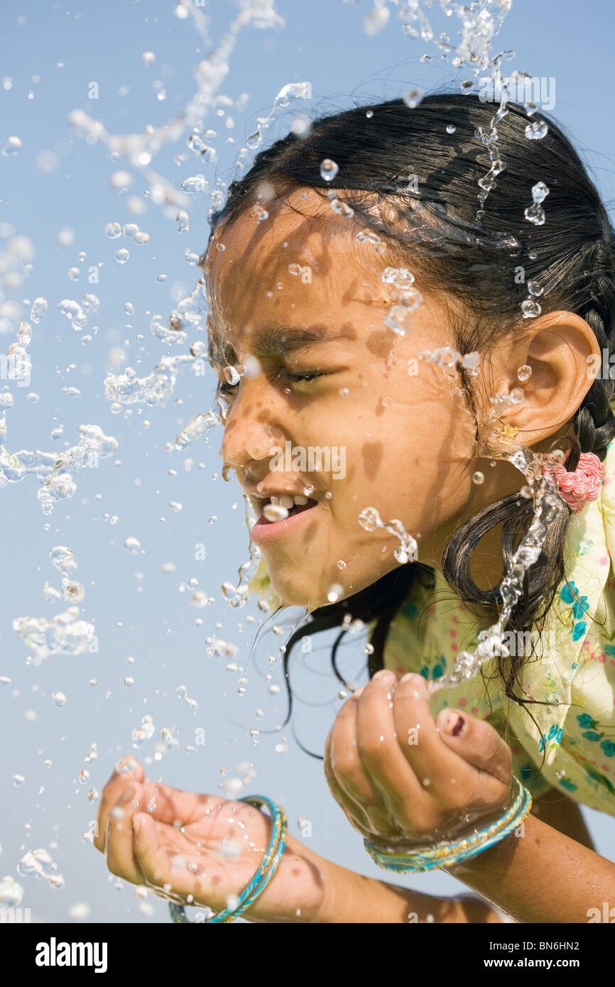 Indian girl splashing water on himself against a blue sky. India Stock ...