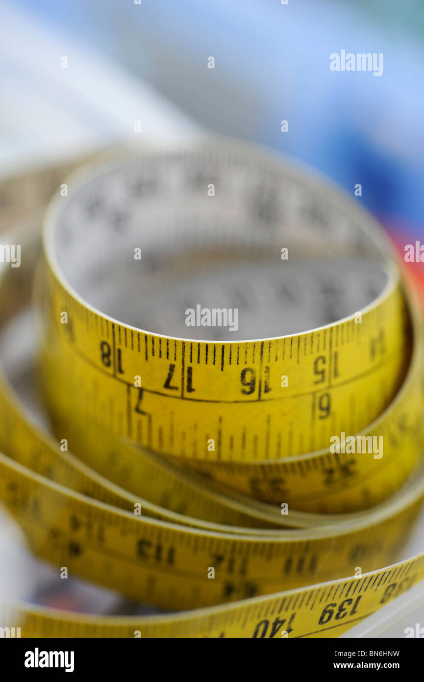 A curled up tape measure on needlework bench Stock Photo - Alamy